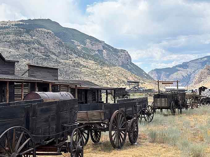 Weathered wooden wagons rest beneath dramatic cliffs, telling stories of journeys that changed a nation forever.