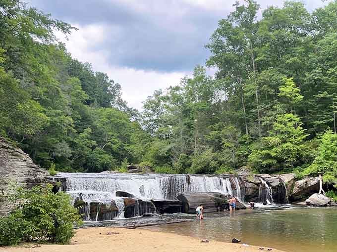 Families wade in the shallow pools while waterfalls cascade gently over smooth stone ledges all around.