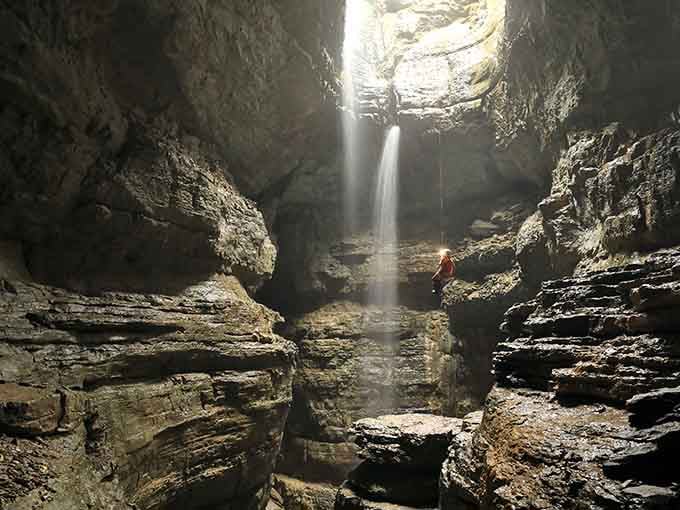 Sunbeams pierce the darkness like nature's own searchlights, illuminating ancient rock layers in this underground cathedral.