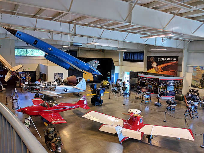 Inside the hangar, vintage aircraft hang suspended overhead while colorful planes create a stunning timeline of aviation history below.