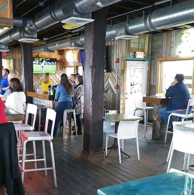 Industrial chic meets coastal comfort where exposed beams and white chairs create the perfect waterside hangout vibe.
