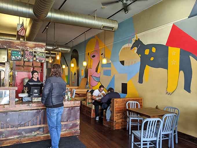 Abstract murals meet industrial charm in this colorful space where art and appetite collide beautifully.