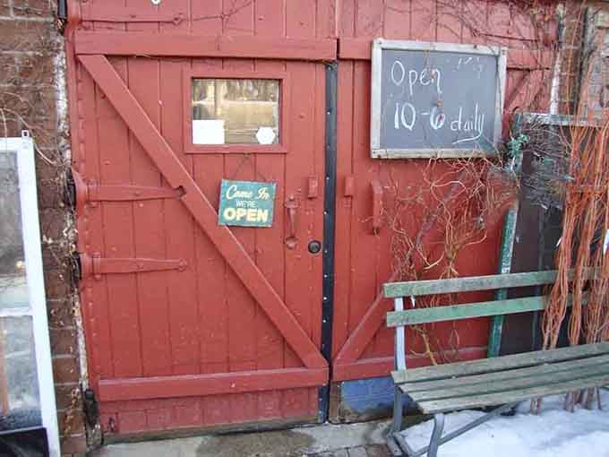 The weathered red door welcomes you daily from 10 to 6, your gateway to decades of collected memories.