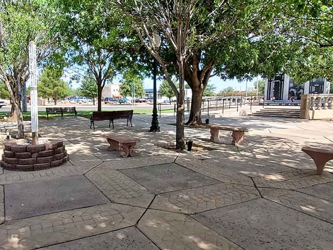 Shaded benches under mature trees offer the kind of peaceful gathering spot that's vanished from most modern towns.