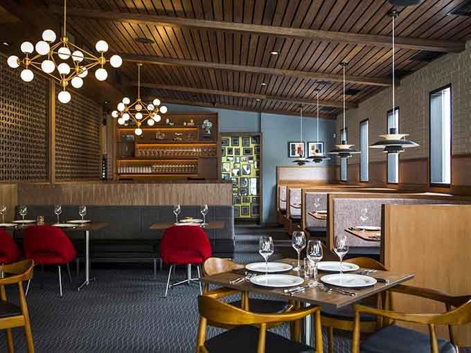 Red chairs, warm wood, and Sputnik lighting transport you straight to the Rat Pack era, minus the cigarette smoke.