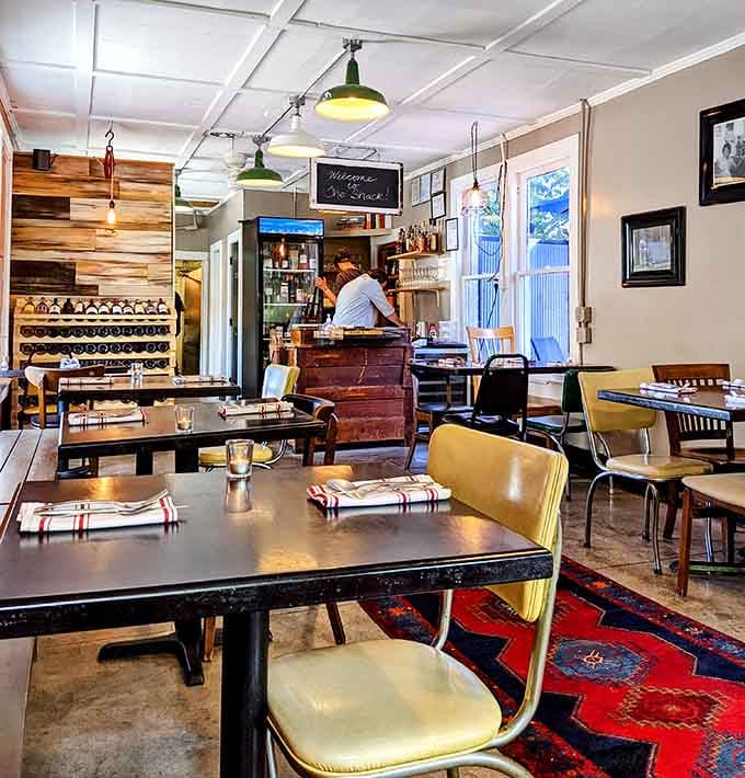 Mismatched chairs, vintage lighting, and an open kitchen create the kind of cozy atmosphere where strangers become friends over pasta.