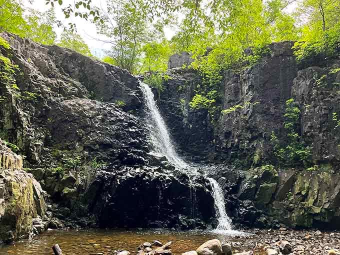 Dark volcanic cliffs cradle this ribbon of water, creating drama worthy of a standing ovation from the trees.