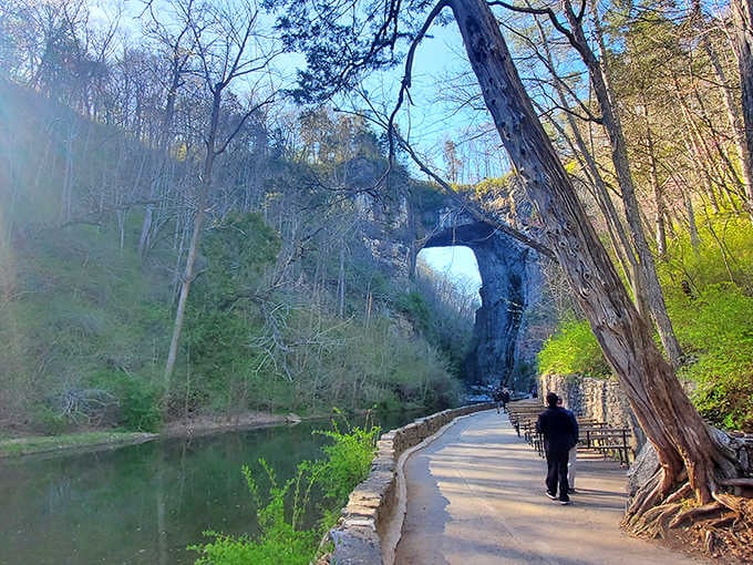 A peaceful walkway leads beneath limestone carved by patient water, framing nature's masterpiece like a postcard from another world.