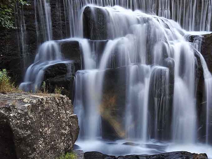 Multiple tiers of silky water tumble down dark stone, creating a mesmerizing display of natural power.