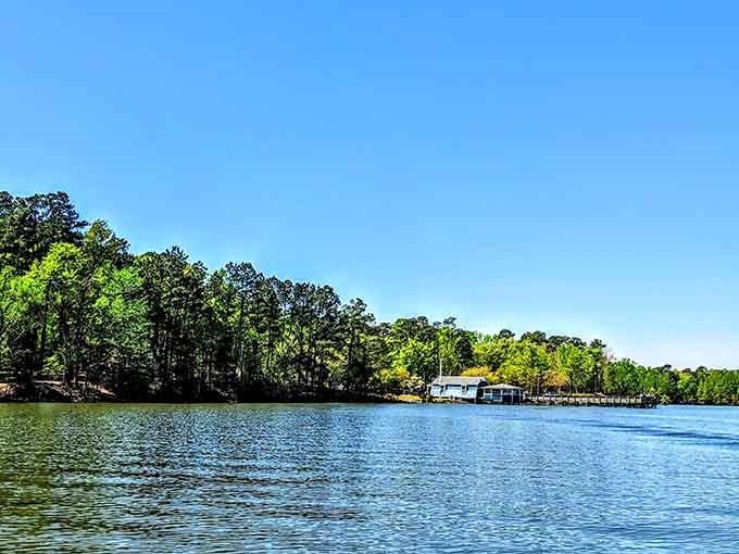 That little white boathouse sits peacefully against emerald forests, looking like a scene from a classic summer postcard.
