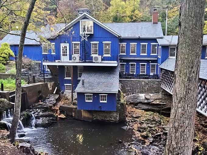 That striking blue mill building perched over rushing water makes dinner feel like a genuine adventure.