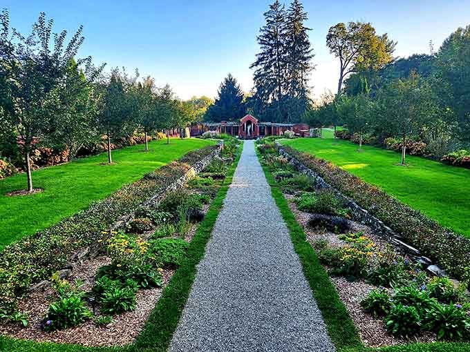 The formal garden path stretches toward that brick pavilion like an invitation to stroll through turn-of-the-century elegance.