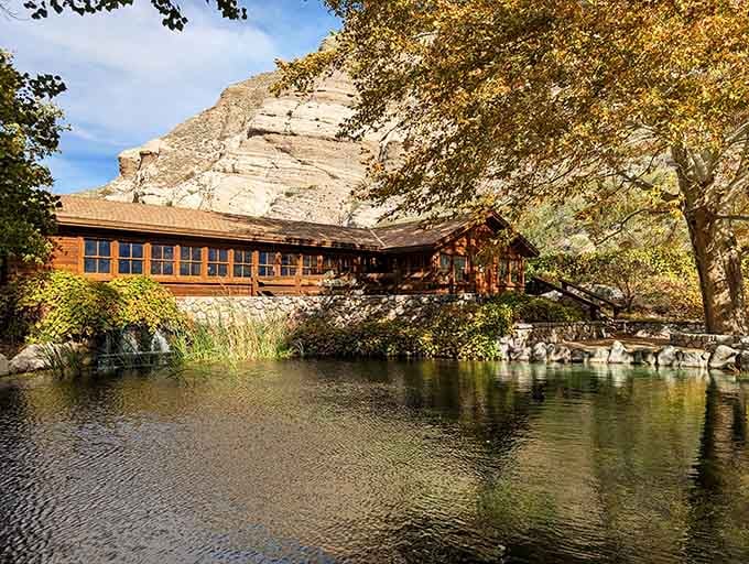 That rustic building nestled against dramatic cliffs looks like nature's own architectural masterpiece come to life.