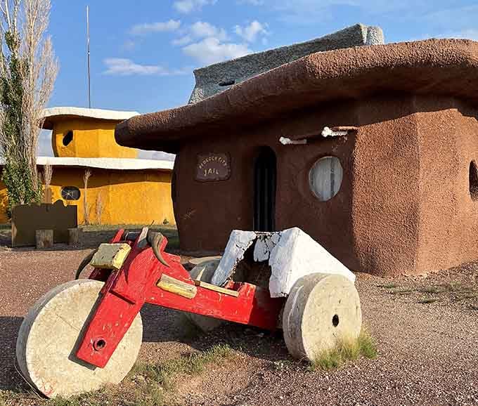 The jail sits next to Fred's iconic foot-powered steamroller, because even Bedrock needed law enforcement and construction.
