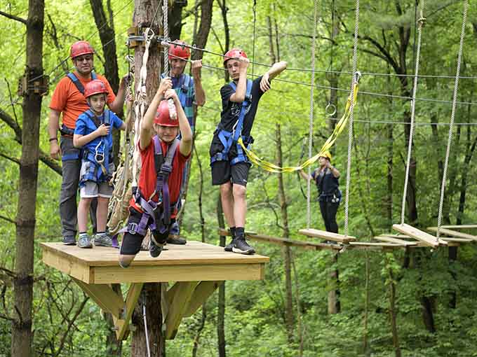 The whole crew gathers on a treetop platform, helmets on, ready to conquer the forest together.