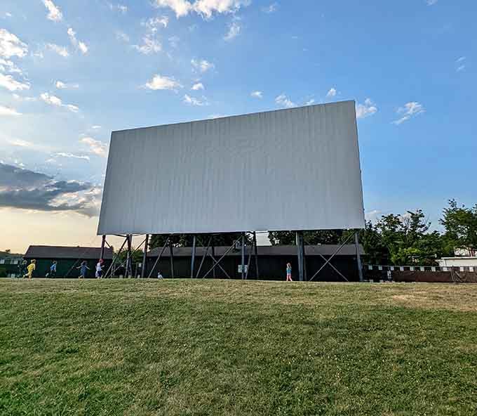 The massive screen stands ready for showtime, a blank canvas awaiting tonight's cinematic adventure under the stars.