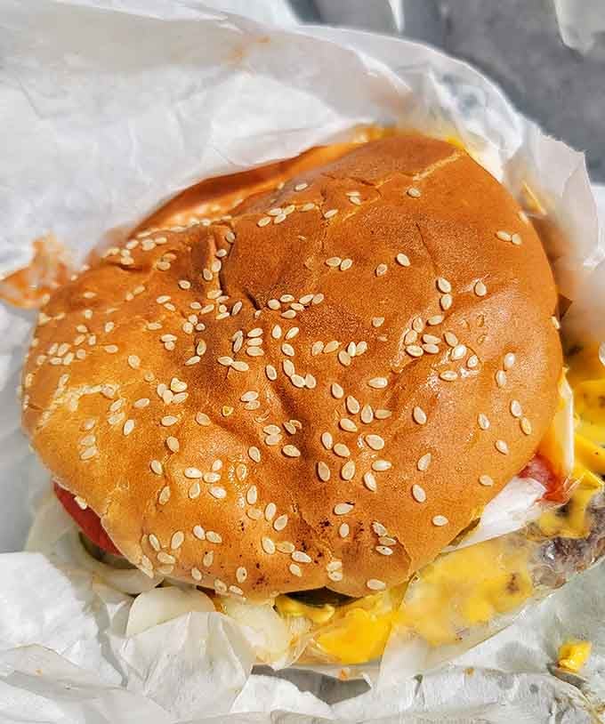 Behold the sesame-studded bun cradling melted cheese and perfectly cooked beef, a masterpiece wrapped in paper instead of a frame.