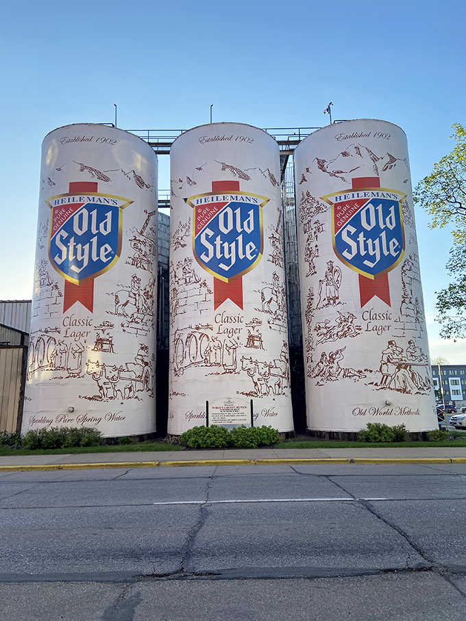 Old Style's classic shield logo towers overhead, turning industrial storage tanks into roadside art that demands attention.
