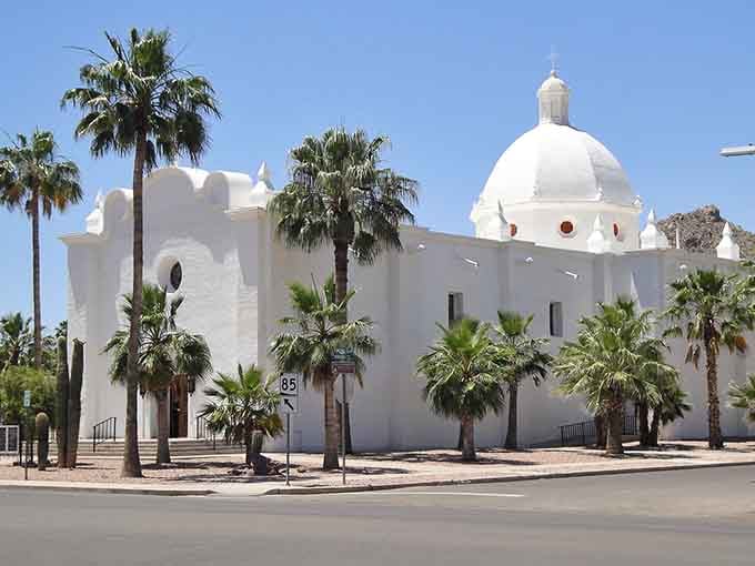 Palm trees frame a stunning white Spanish mission church rising from the desert like an architectural mirage.