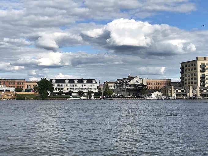 Waterfront living at its finest, where historic buildings reflect in the calm bay under dramatic Michigan skies.