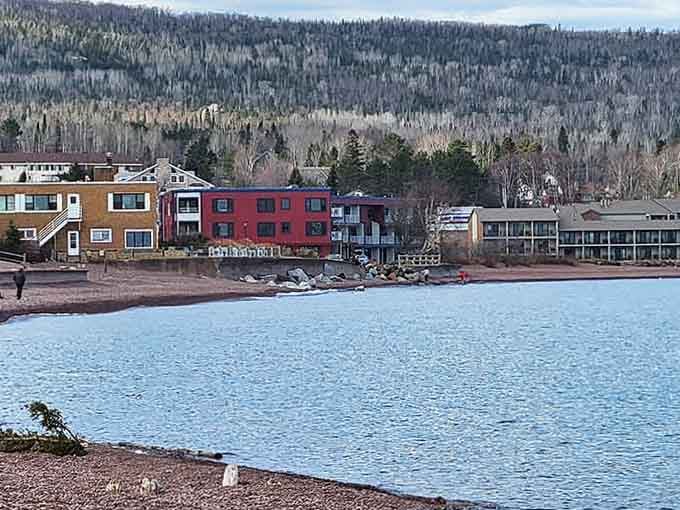 Colorful lakeside buildings nestle against forested hills like a Bob Ross painting that decided to become three-dimensional reality.