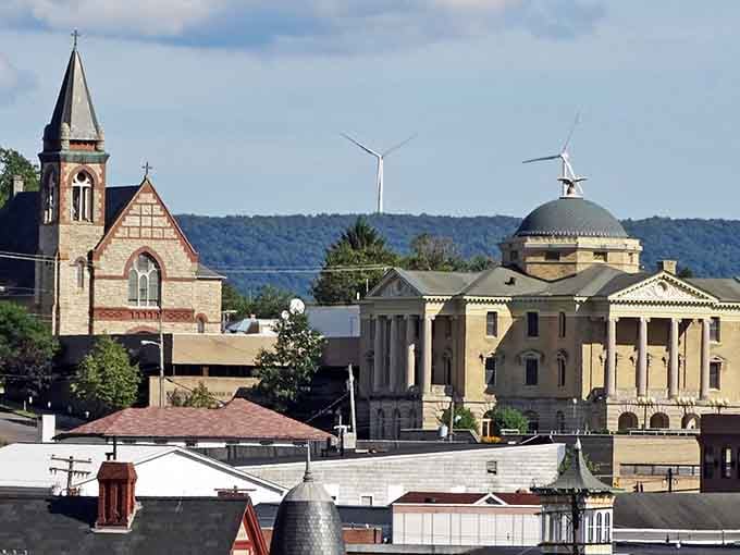 Mountain town architecture meets small-town America where church steeples and historic buildings create an unforgettable skyline against green hills.