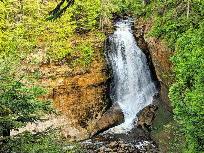 Layers of ancient rock tell stories in rust and cream, while spring green frames this geological masterpiece.