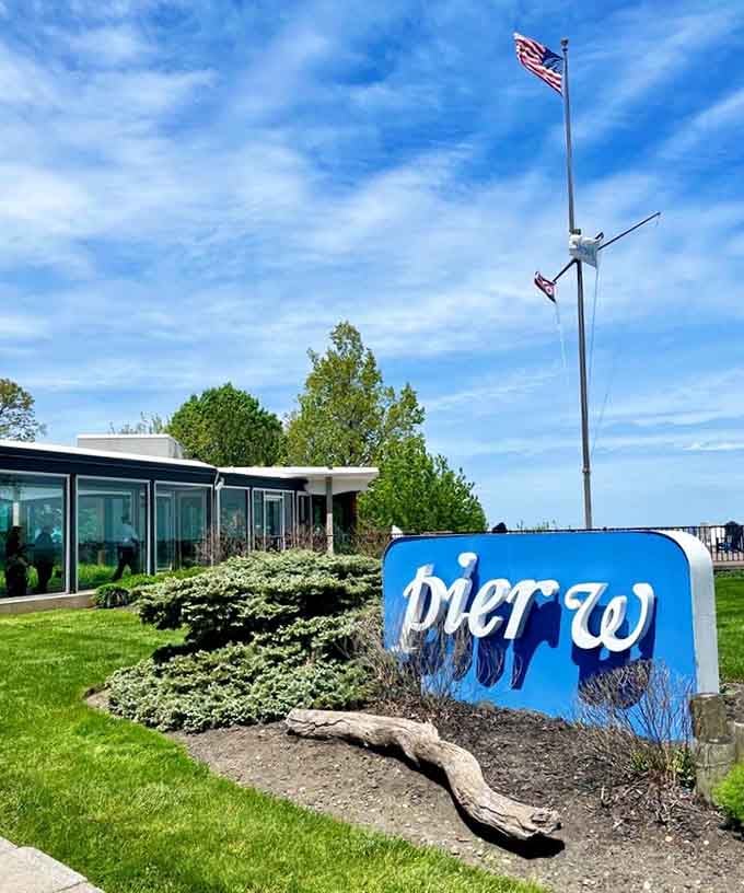 The modern blue sign and manicured landscaping hint at the upscale lakefront dining experience waiting inside those glass walls.