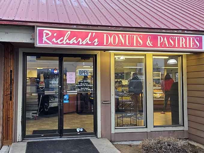 That pink and white sign glows with retro charm, like something from a simpler time when donuts ruled breakfast.