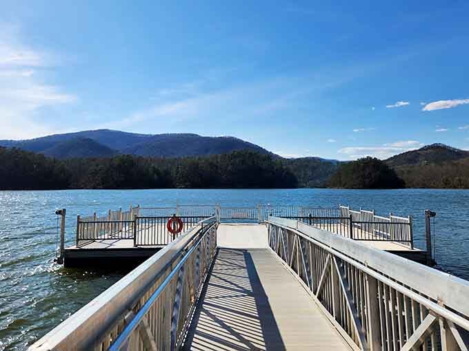 Serene boat launch reveals turquoise waters nestled between majestic blue ridge peaks at golden hour.