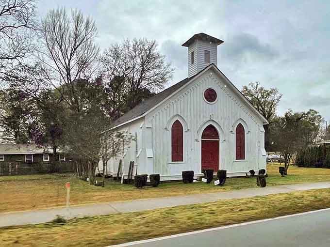 The white chapel with red doors stands proud and pristine, a beacon of community faith and tradition.