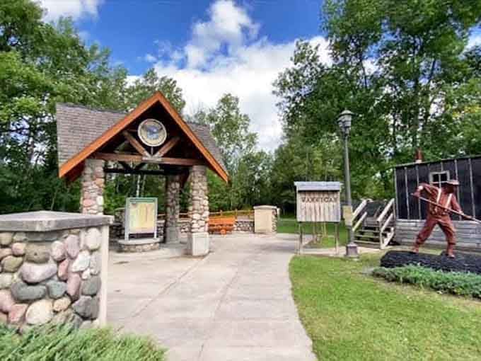 A stone gateway, a metal sentinel, and towering trees welcome you to McGrath like a handshake from the forest itself.
