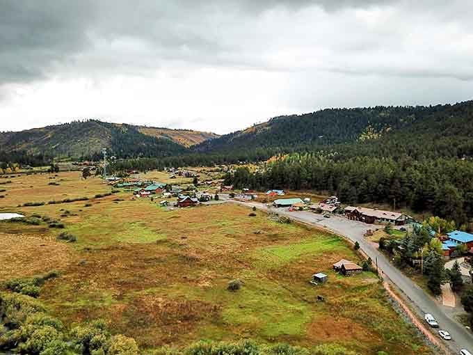 Storm clouds gather over emerald meadows and forest ridges in a landscape that belongs on a postcard.