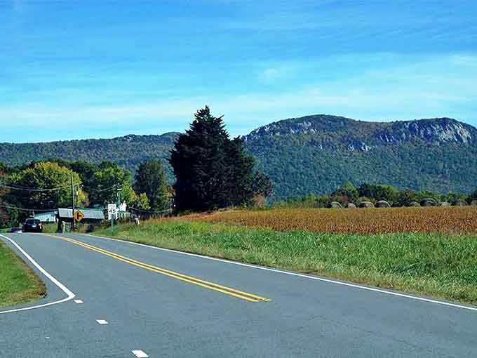 Blue skies frame the mountain backdrop while the open road stretches through farmland that's been here for generations.