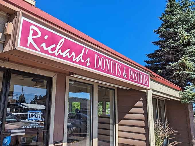 Blue skies frame this classic donut shop entrance, where pastries and possibilities await behind those welcoming glass doors.