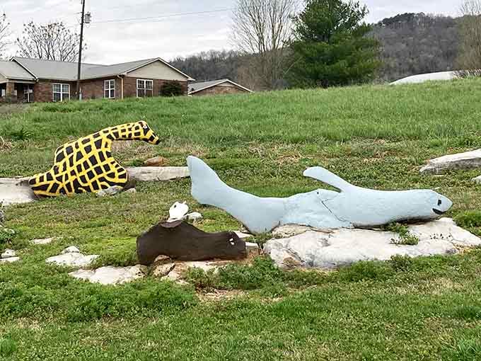 A yellow lattice gator leads this quirky parade of painted sculptures resting on grass like a surreal safari.
