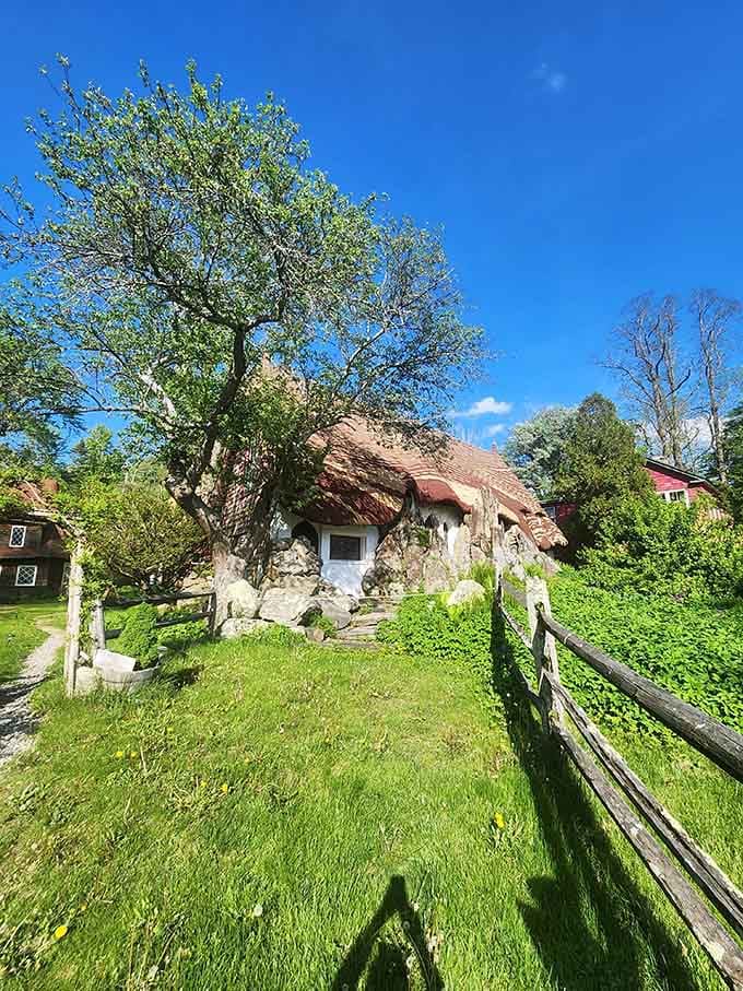 A rolling stone cottage with a fairy-tale roof, rustic fence, and grass so green it practically glows.