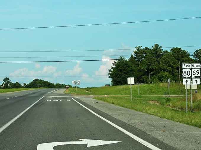 Classic American highway stretching toward puffy clouds, where Routes 80 and 69 intersect with pure Southern tranquility.