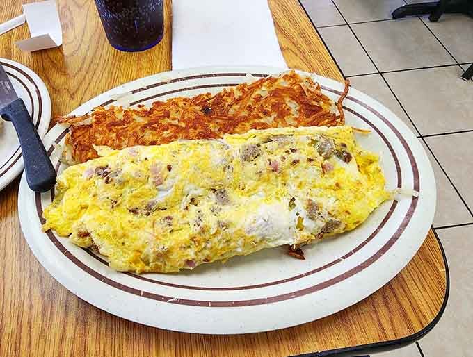Behold the omelet in all its golden glory, paired with hash browns that understand their crispy assignment perfectly.