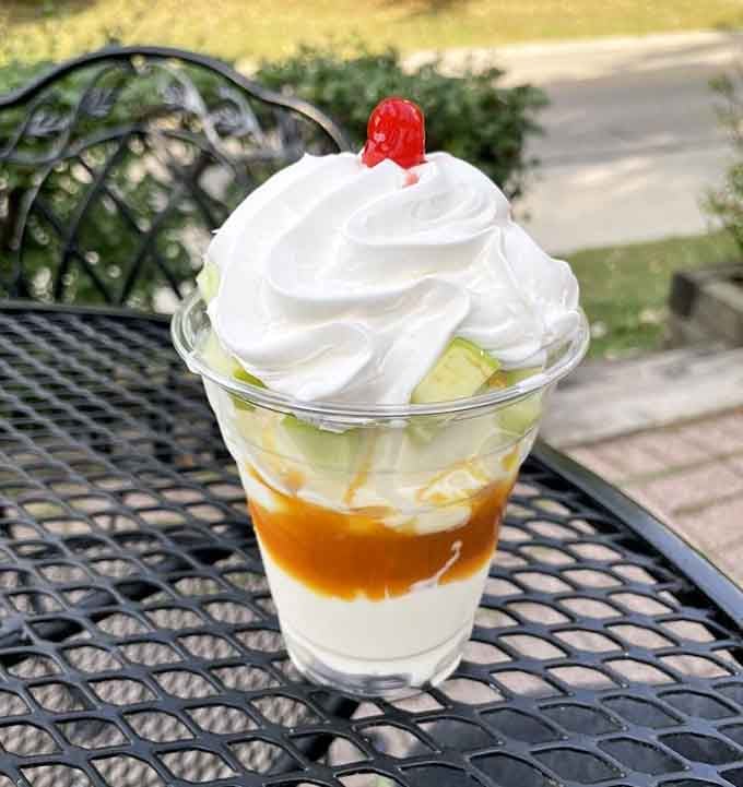 Caramel cascading over vanilla custard like liquid gold, topped with whipped cream that's basically a fluffy cloud with a cherry on top.