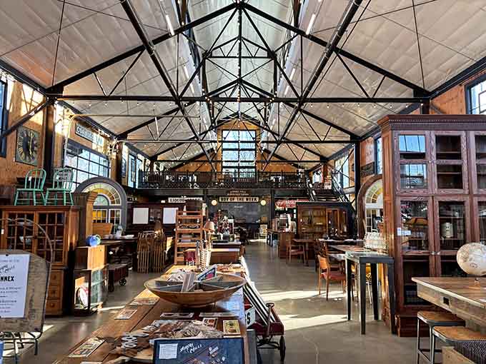 The soaring industrial ceiling frames a collector's dream, where furniture and curiosities create their own architectural masterpiece below.