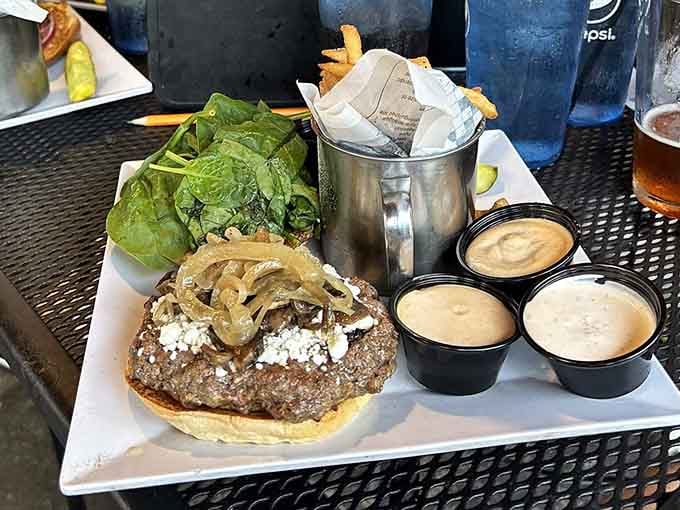 Behold the burger that requires an engineering degree to eat, served with sides and multiple sauce options for strategic planning.