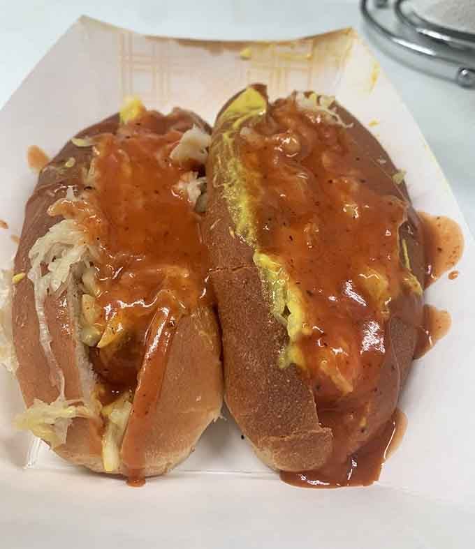 Two perfectly dressed hot dogs glistening with chili and sauerkraut, proof that simplicity executed brilliantly beats complexity every time.