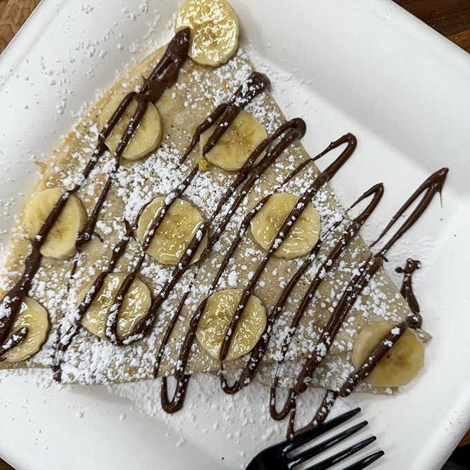 Sliced bananas and chocolate drizzle on a perfectly thin crepe, dusted with powdered sugar like fresh Arizona snow.