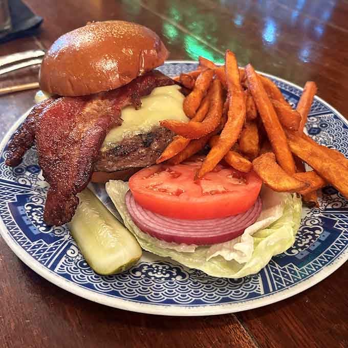 Bacon draped over a juicy burger with sweet potato fries is basically the American dream on a plate.