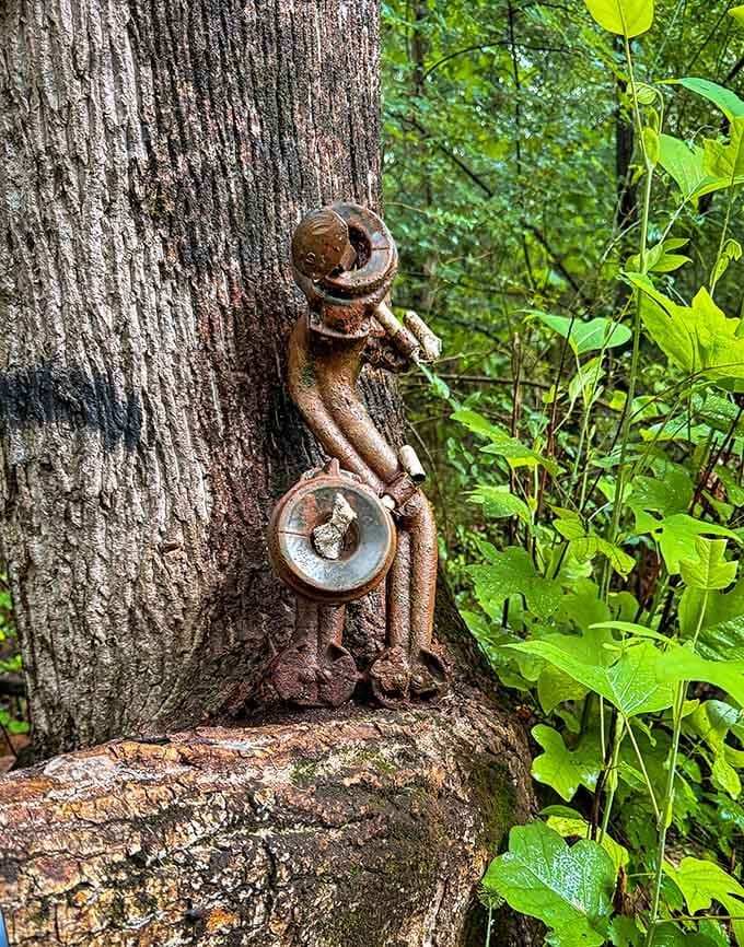 This rusty figure's been hugging this tree longer than most marriages last, proving that art and nature make excellent companions.