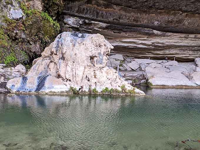 That pale boulder sits like a patient sentinel, watching swimmers discover what thousands of years of erosion created.