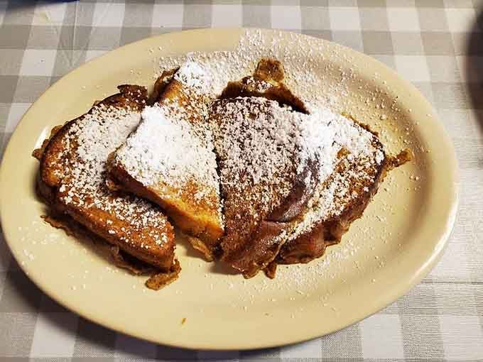 French toast dusted with powdered sugar like fresh snow on golden, buttery mountains of deliciousness.