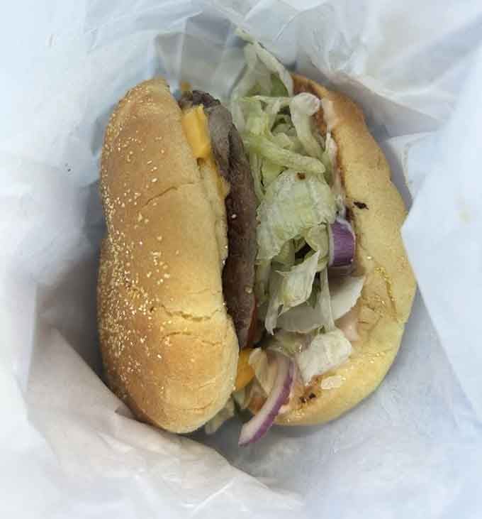 A cheeseburger wrapped in paper, topped with lettuce and onion, looking exactly like happiness should look.
