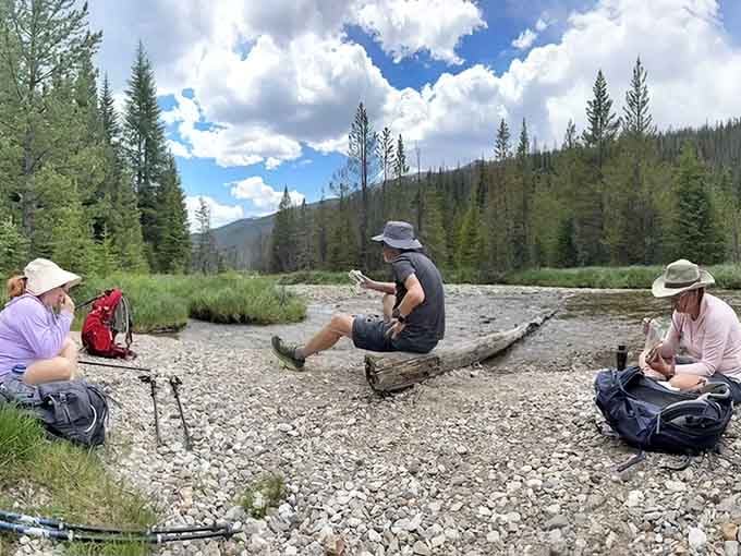 Perfect spot for contemplation: hikers pause by the river, soaking in mountain solitude and snack time.